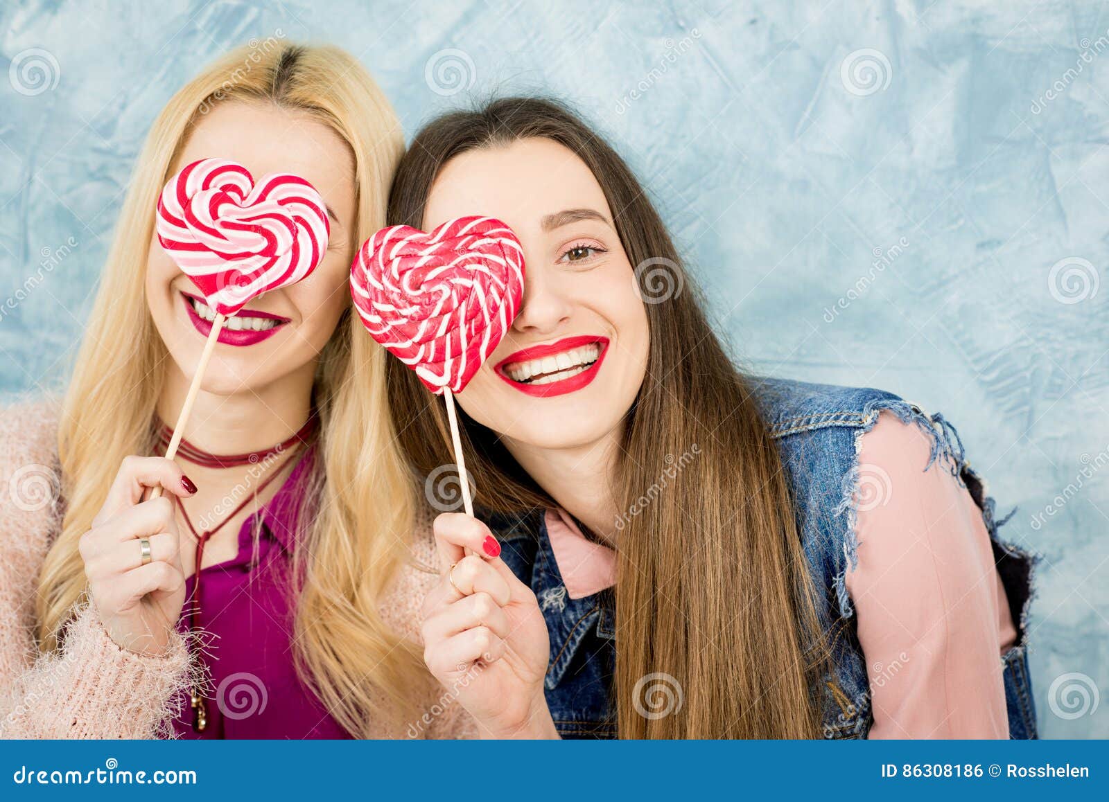 Female Friends with Candy on the Blue Background Stock Photo - Image of ...