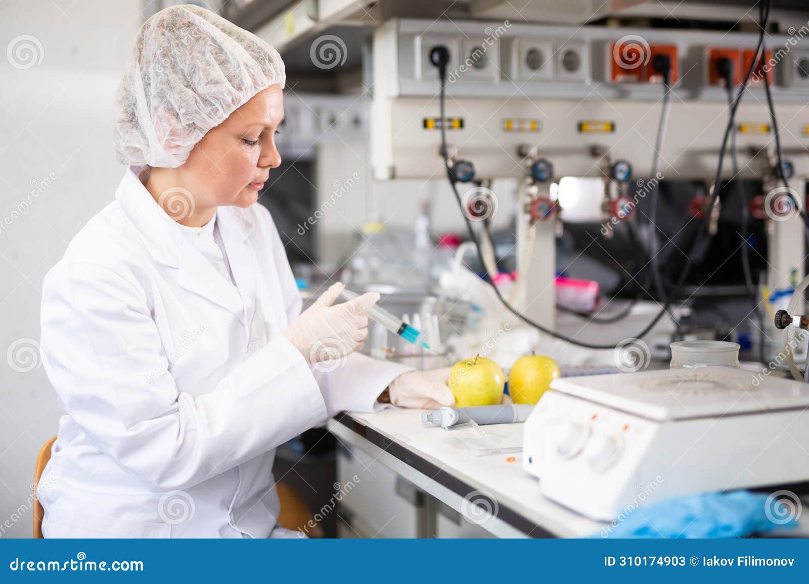 Female Geneticist Working in Laboratory, Injecting Additives into Apple ...