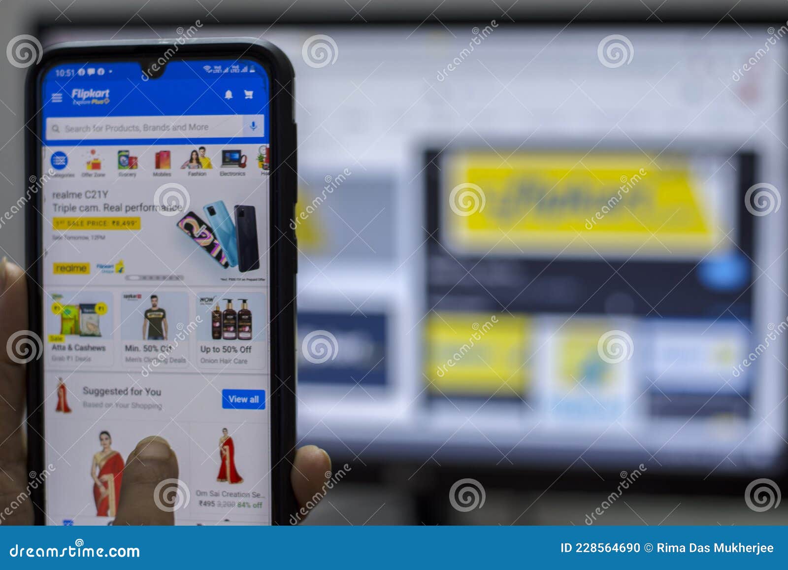 A Female Hand Holding a Android Smart Phone in Front of a Desktop ...