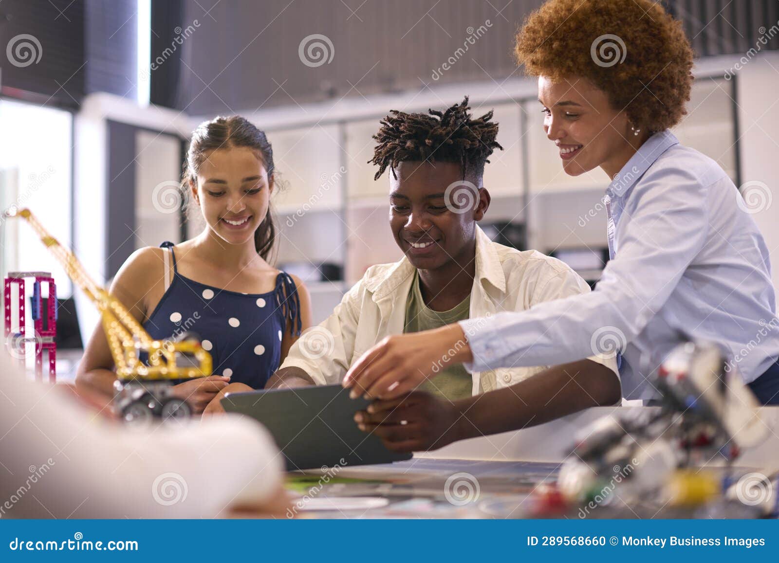 Female High School Teacher with Digital Tablet Helping Students in STEM ...