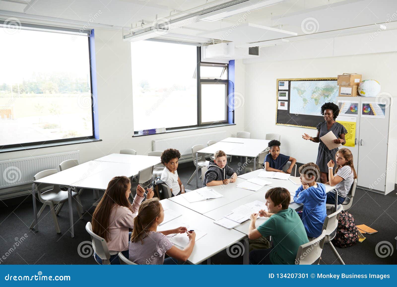 Female High School Tutor Standing by Table with Students Teaching ...