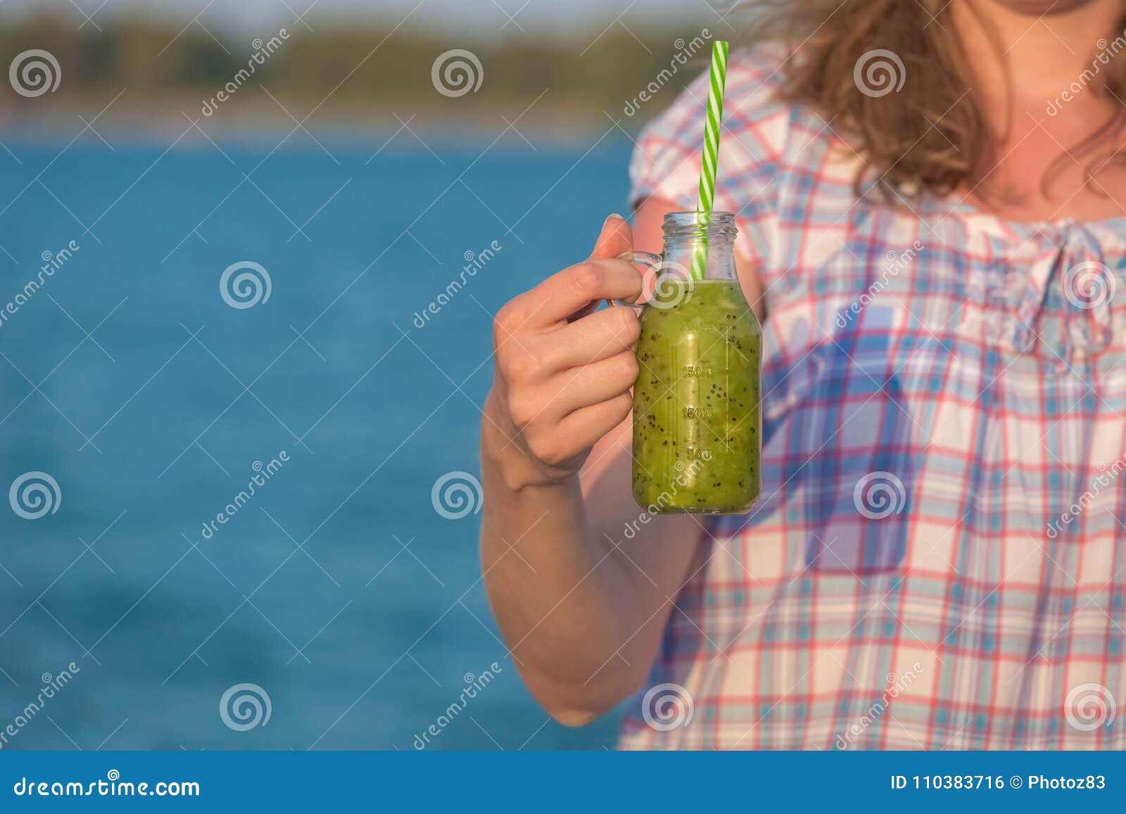 Female Holding A Glass Bottle Of Fresh Kiwi Smoothie Outdoors Stock
