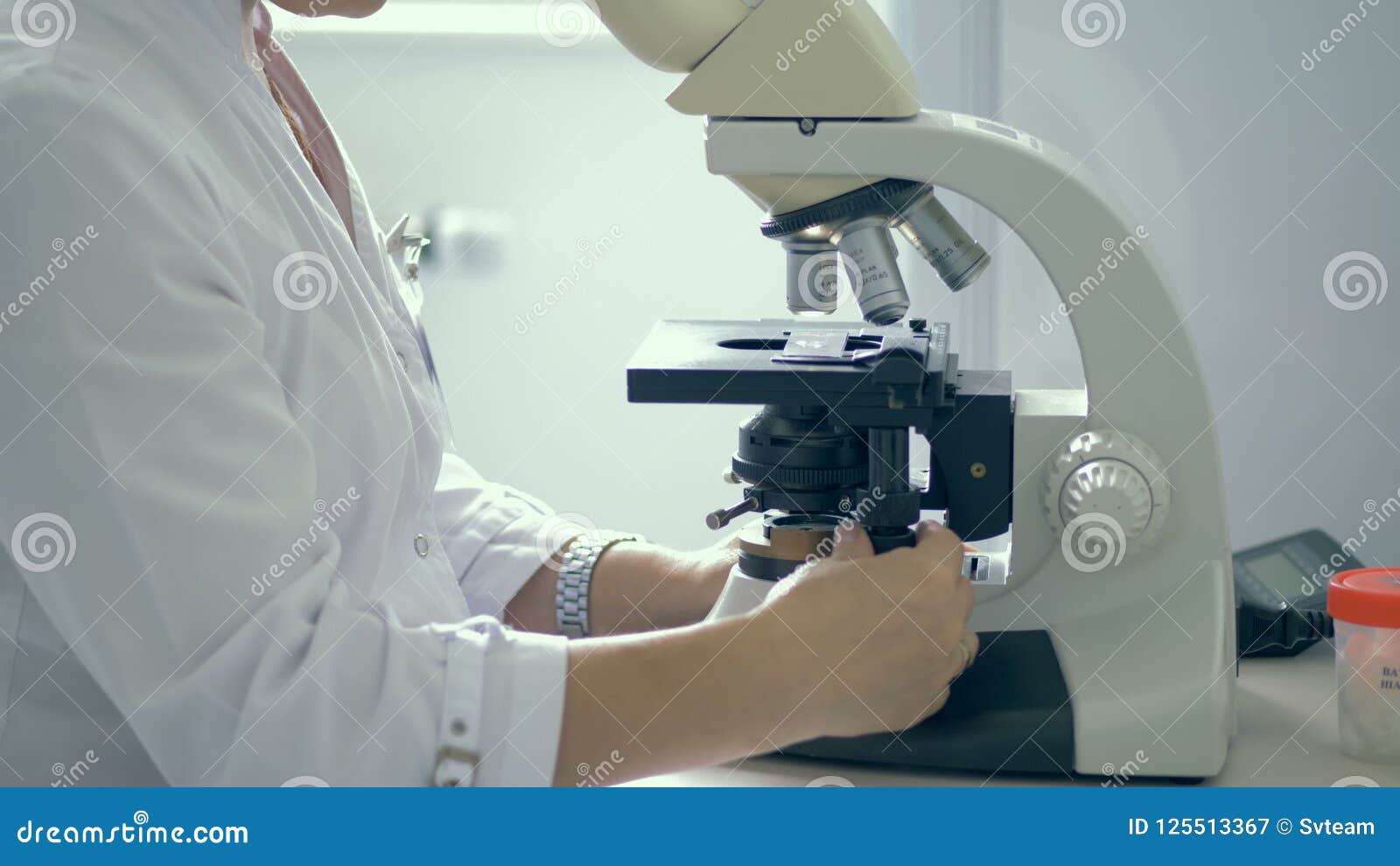 Female Lab Worker is Regulating a Microscope while Watching into it ...