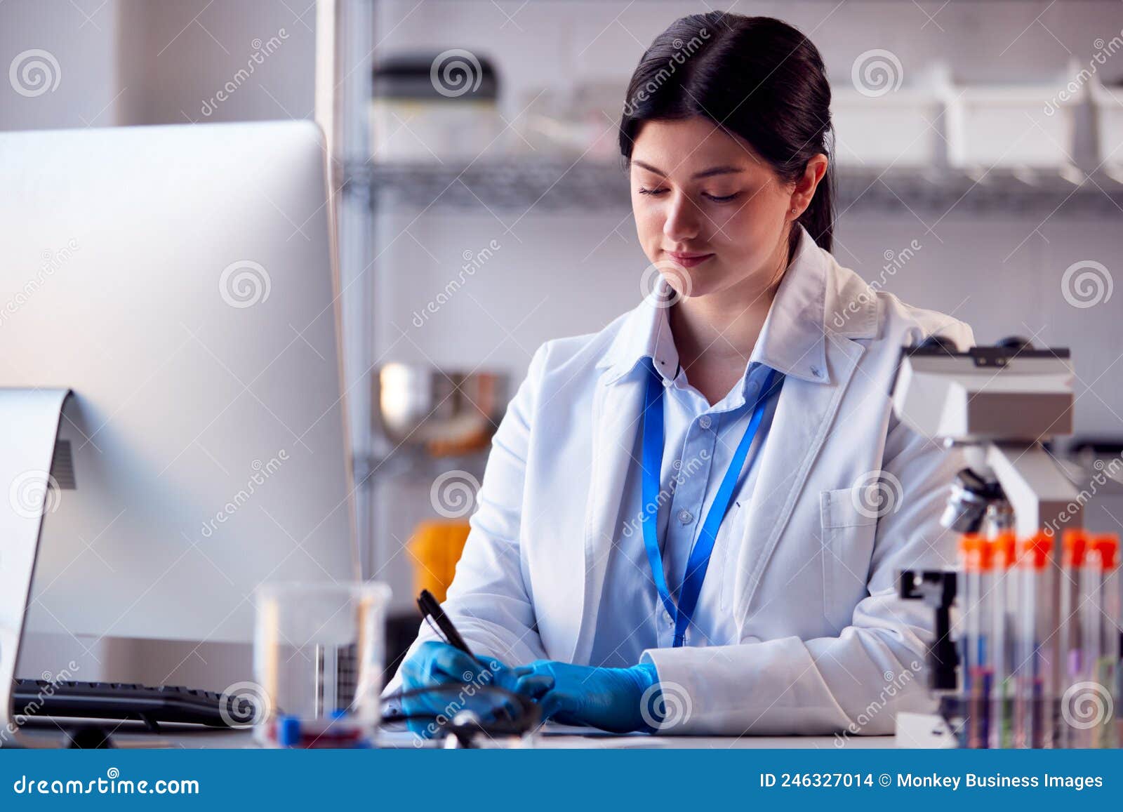 Female Lab Worker Wearing White Coat Recording Test Results on Computer ...