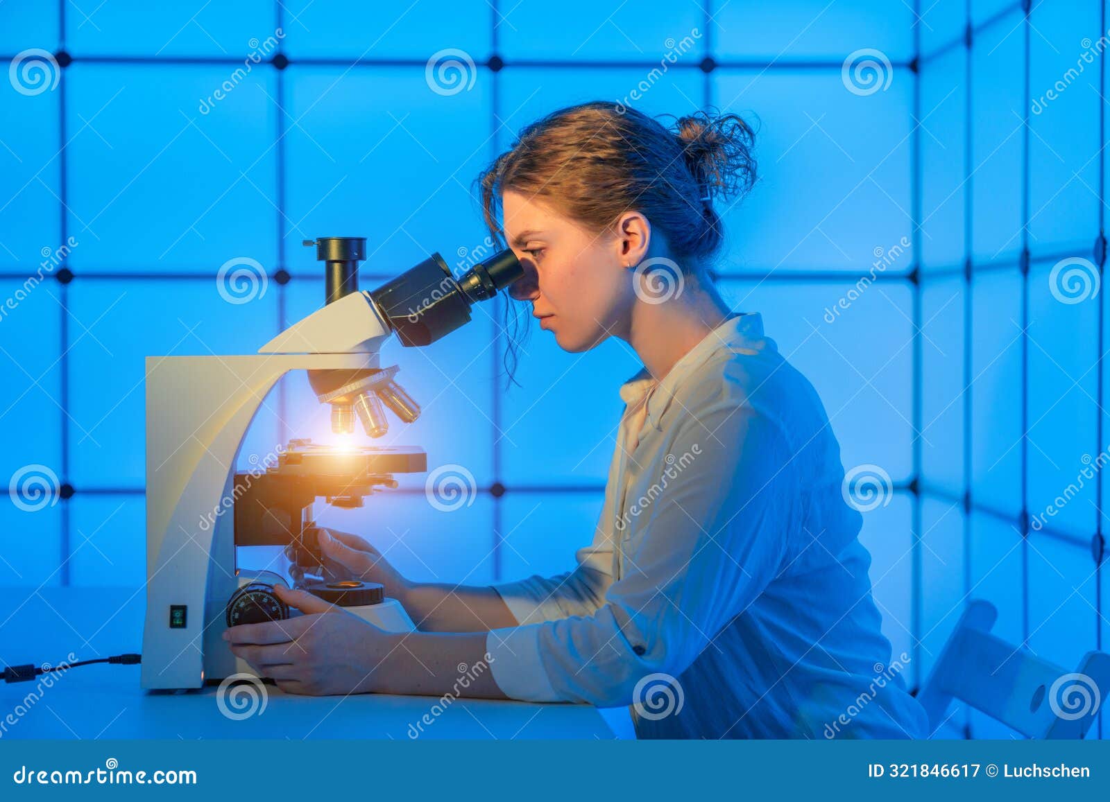 Female Laboratory Assistant in a Laboratory with Blue Glowing ...