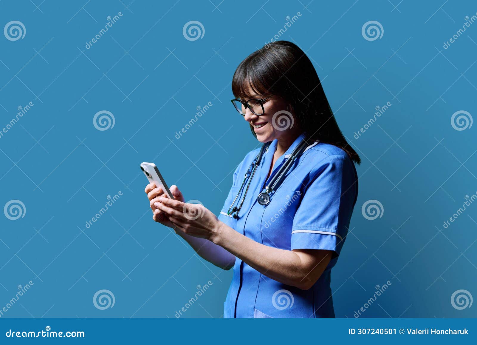 Female Nurse Using Smartphone, Profile View on Blue Studio Background ...