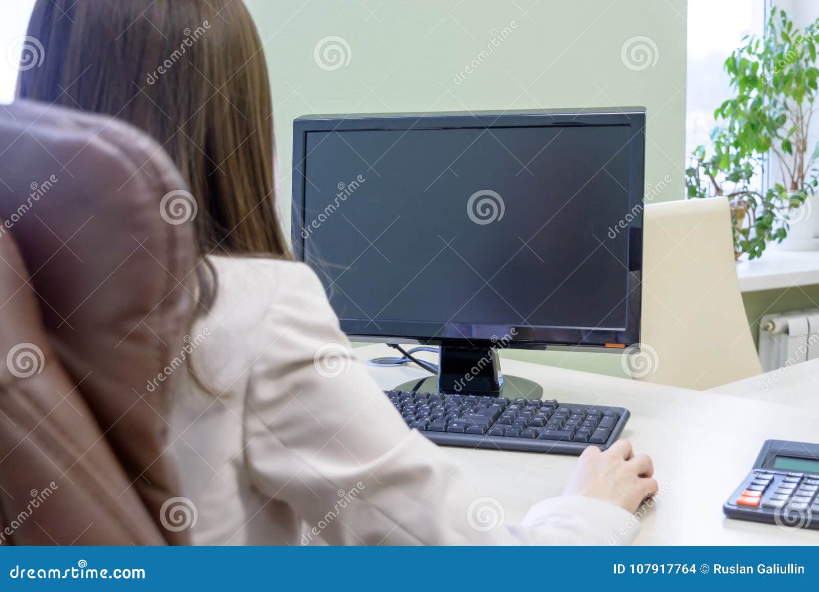 Female Office Worker Sits in a Leather Chair in Front of a Computer and ...