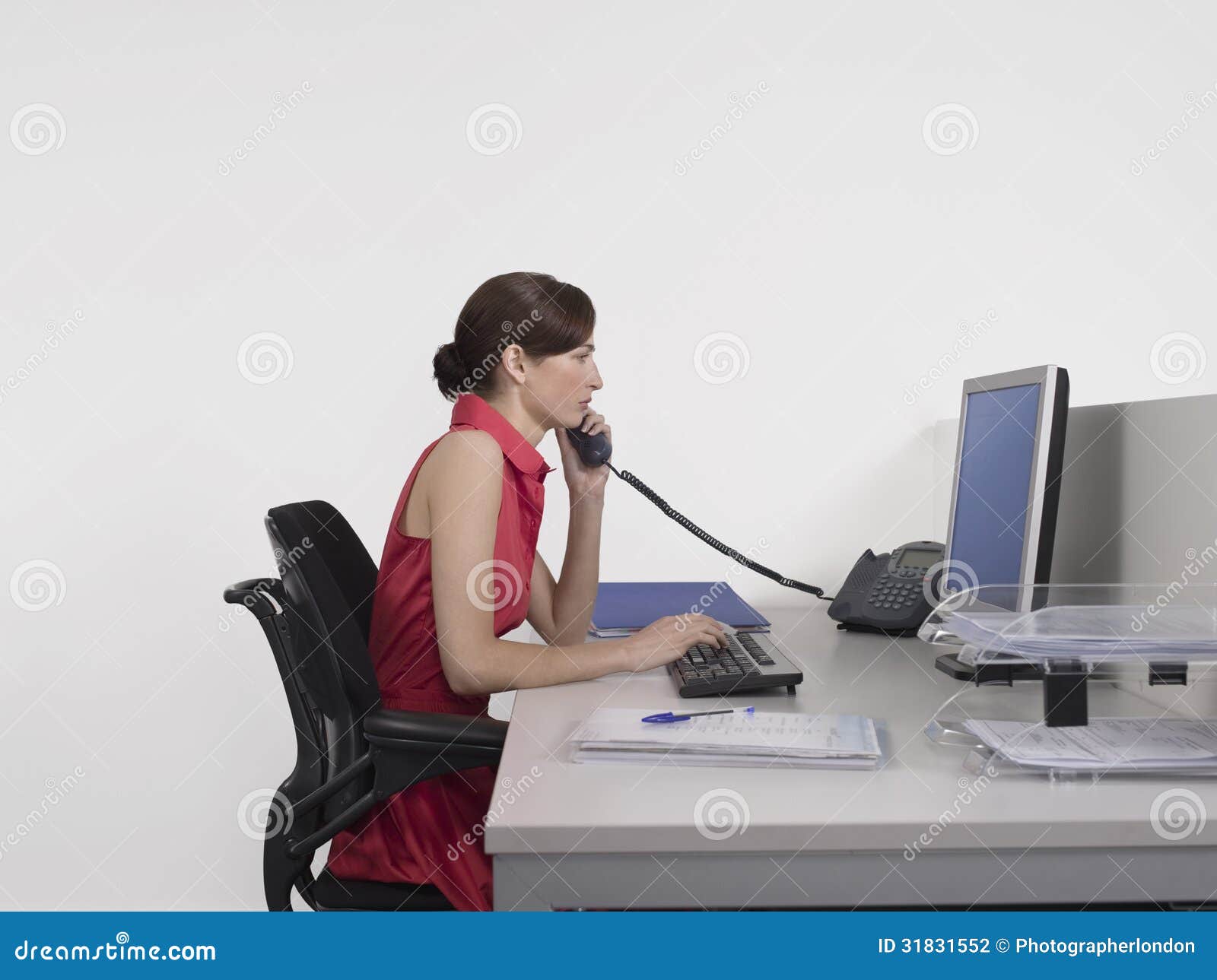 Female Office Worker Using Computer and Telephone at Desk Stock Photo ...