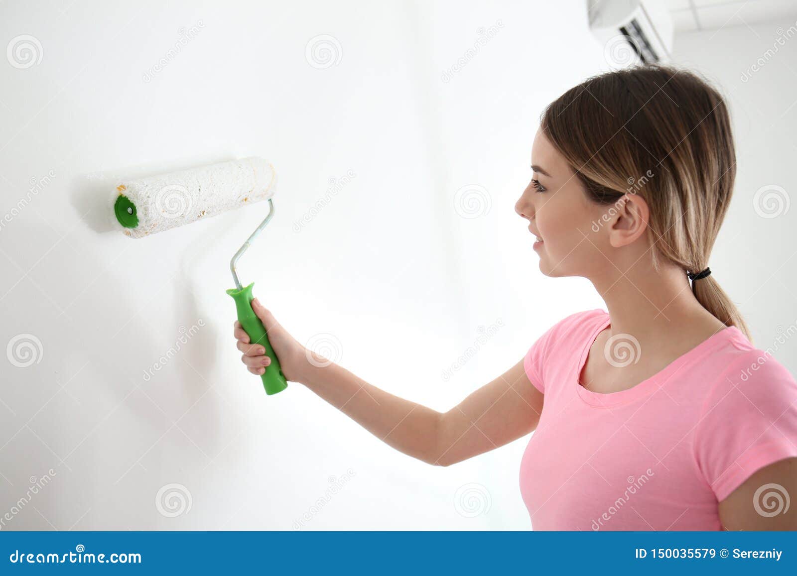 Female Painter Using Roller for Refurbishing Color of Wall Indoors ...
