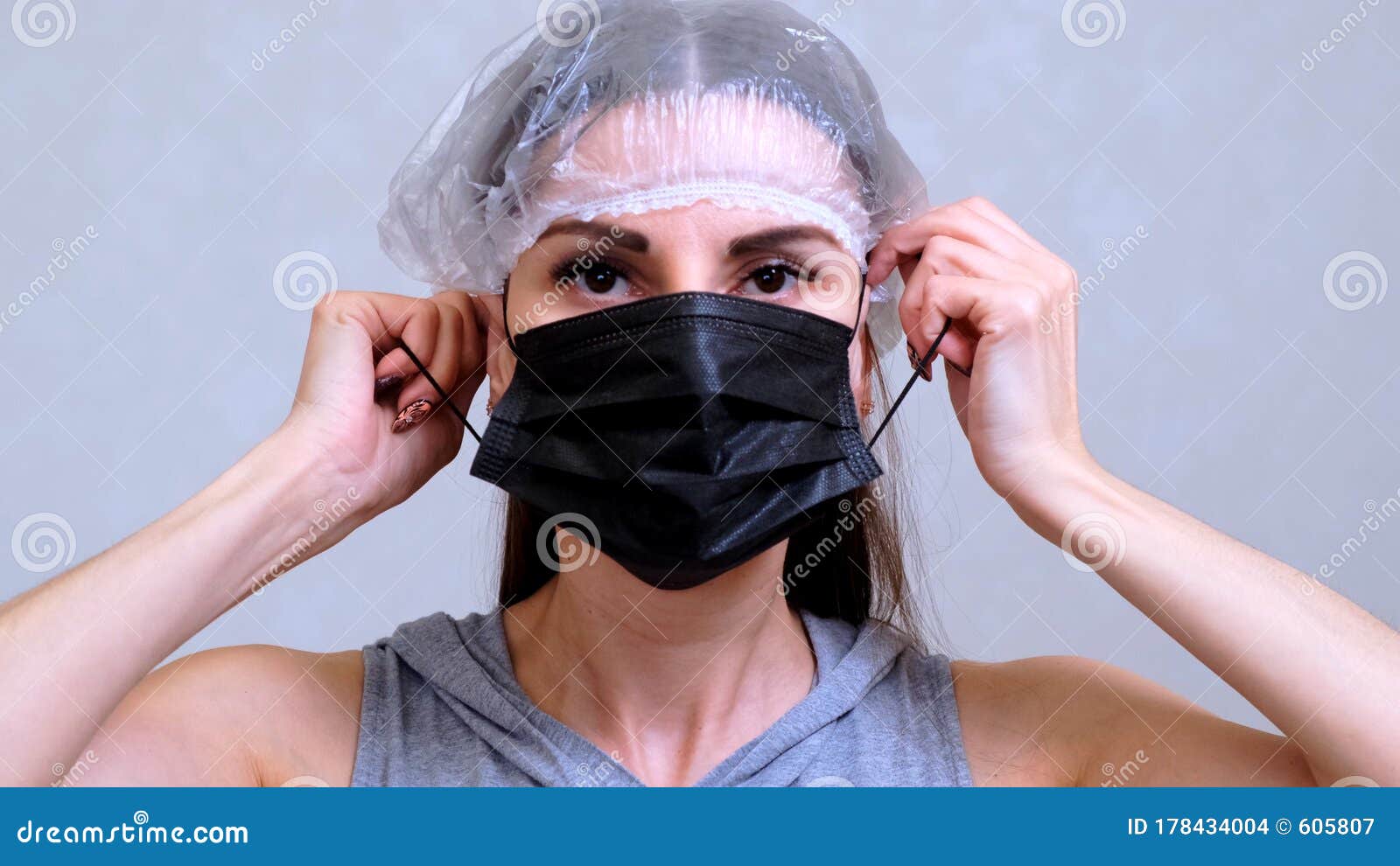 Female Patient in a Disposable Cap Puts on a Black Protective Mask ...