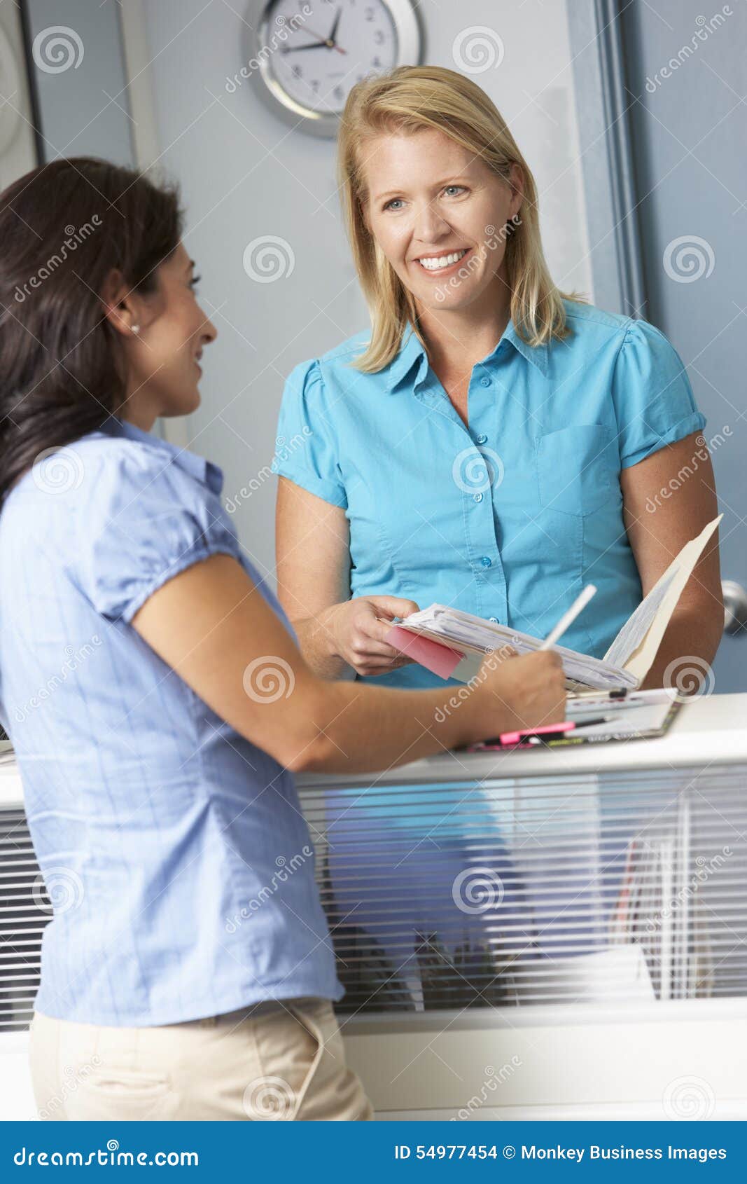 Female Patient with Receptionist in Doctors Waiting Room Stock Photo ...