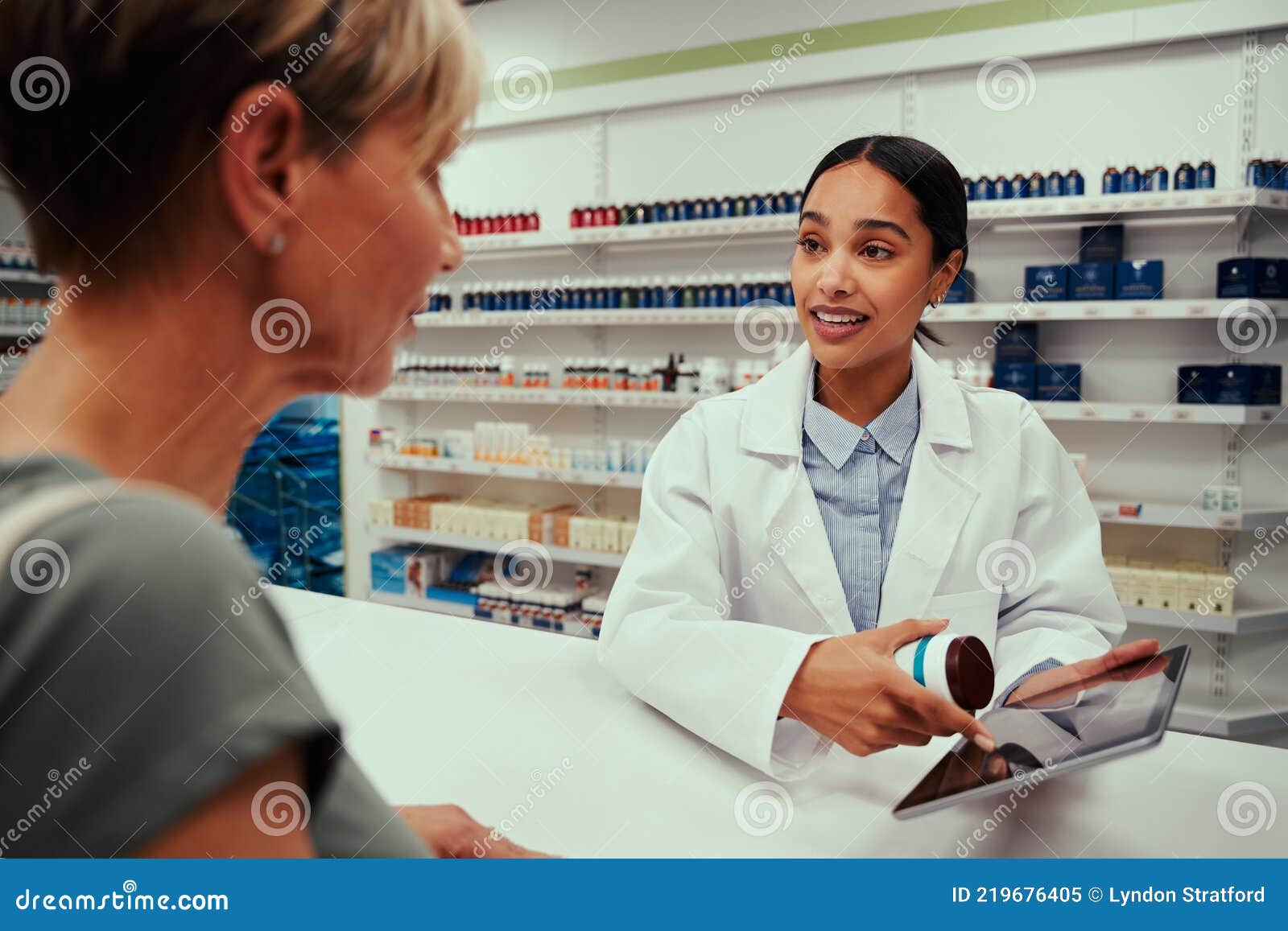 Female Pharmacist Guiding Customer with Tablets by Showing Something on ...