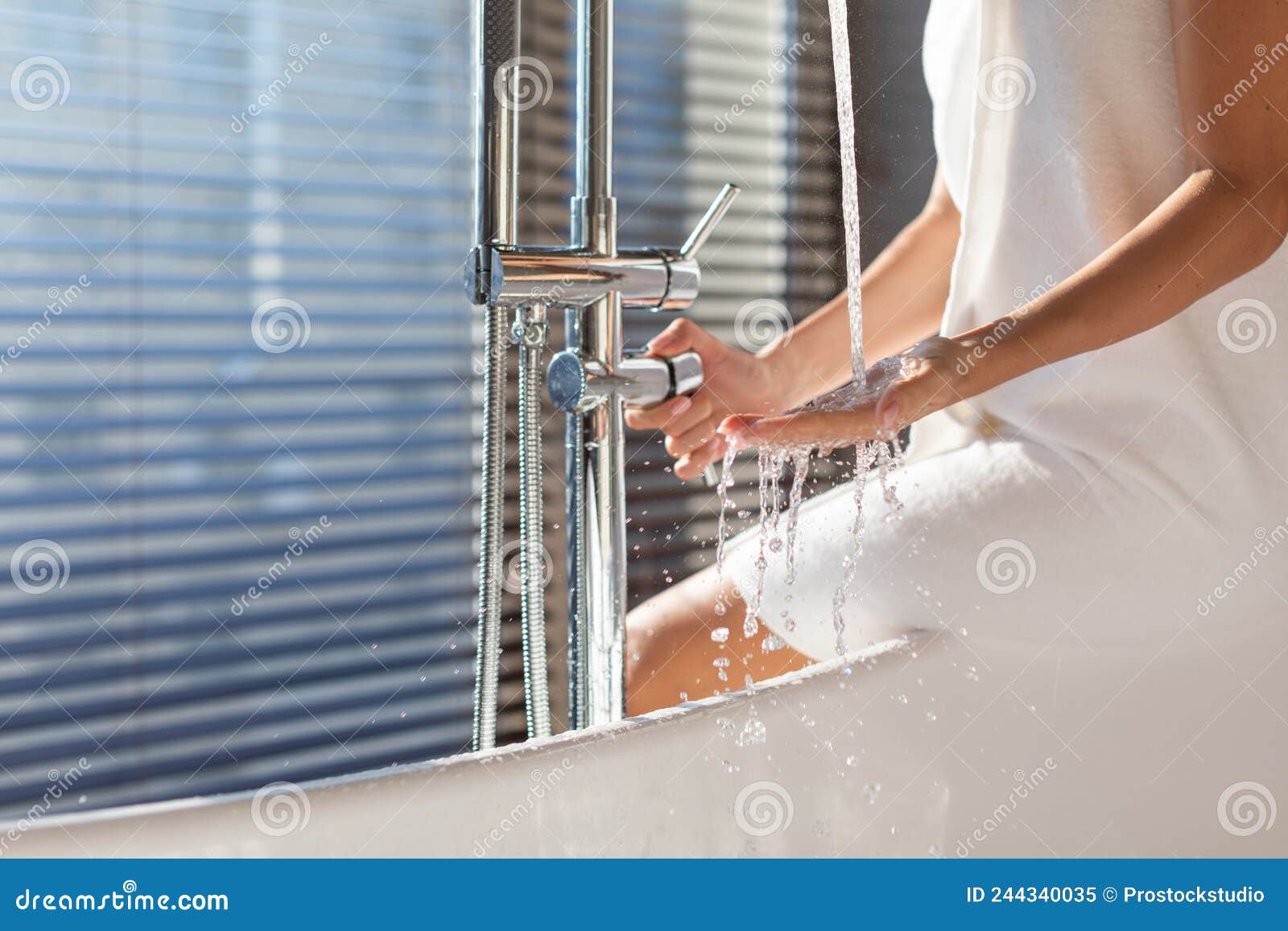 Female Playing With Water Flowing From Tap While Sitting On Bathtub