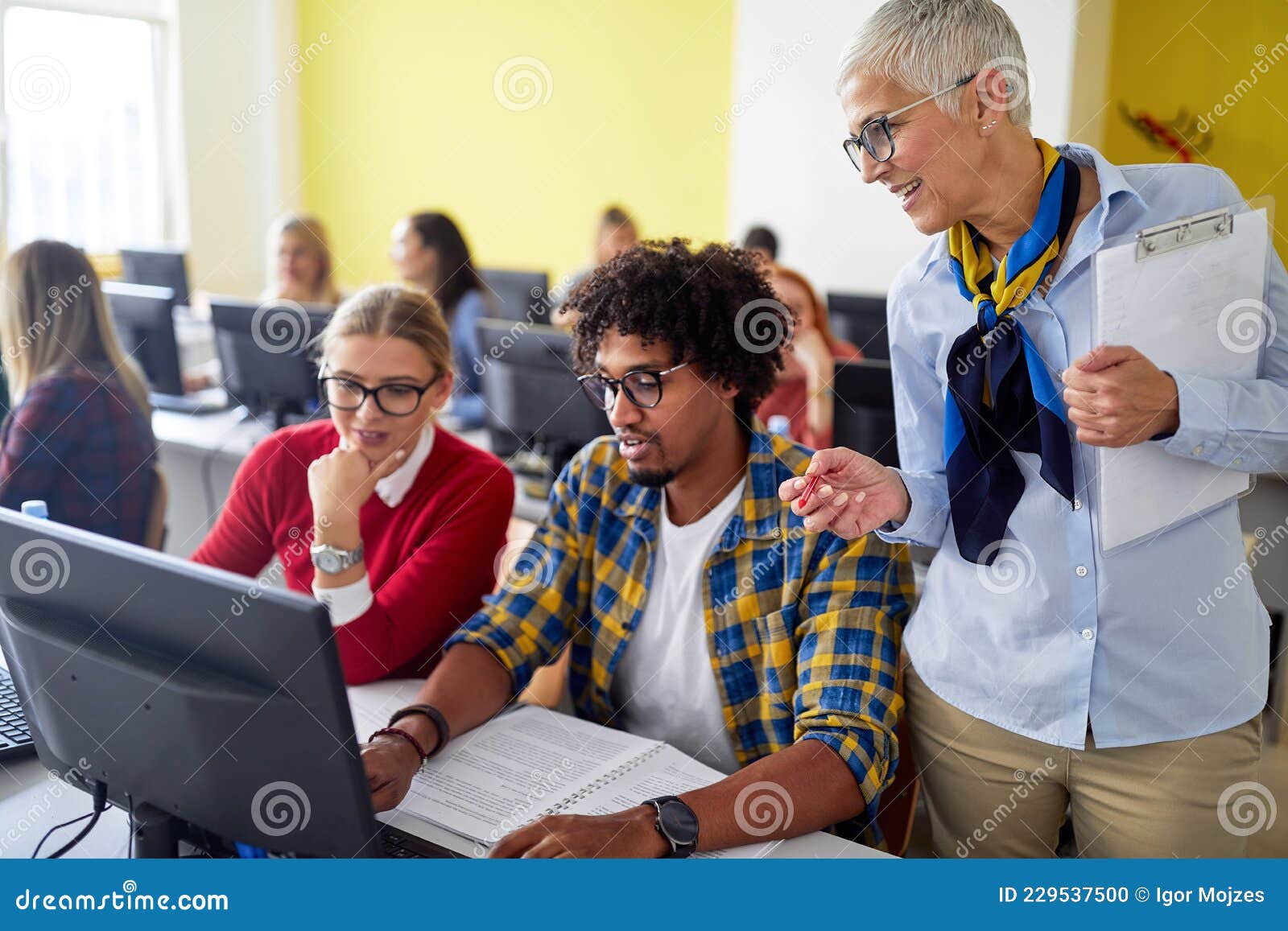 A Female Professor Checking Work of Students at the Informatics Lecture ...