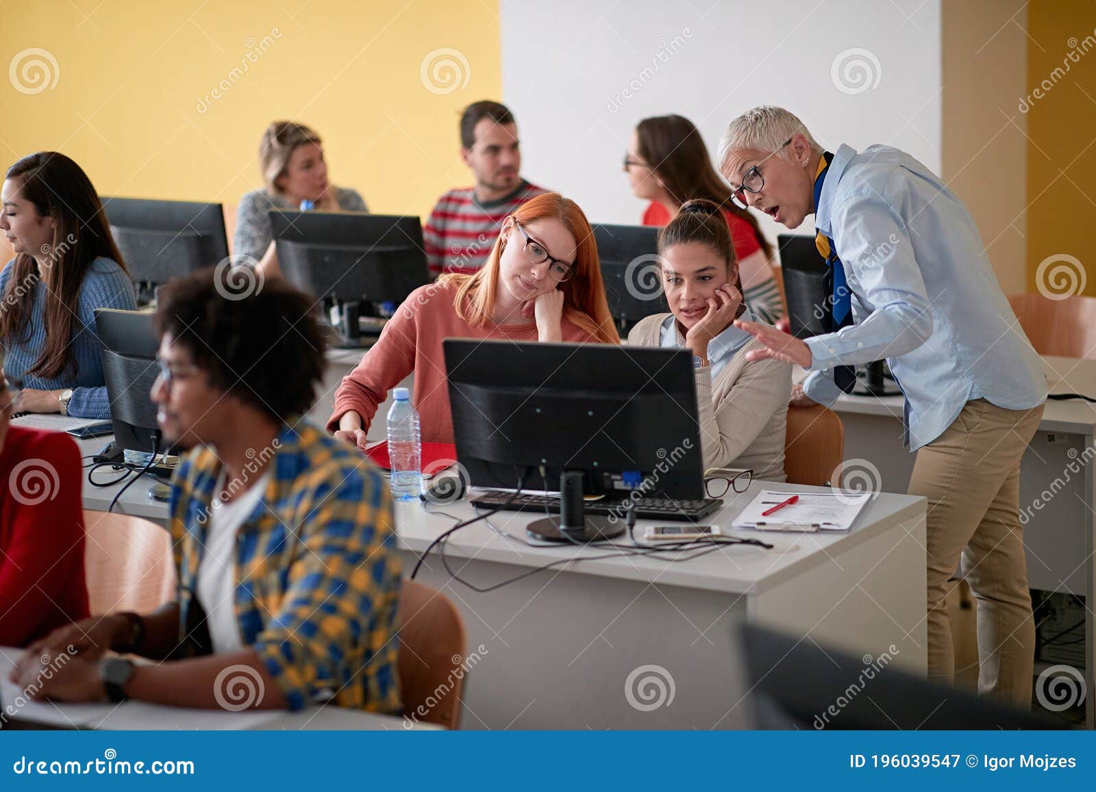 Female Professor Correcting the Work of Students at an Informatics ...