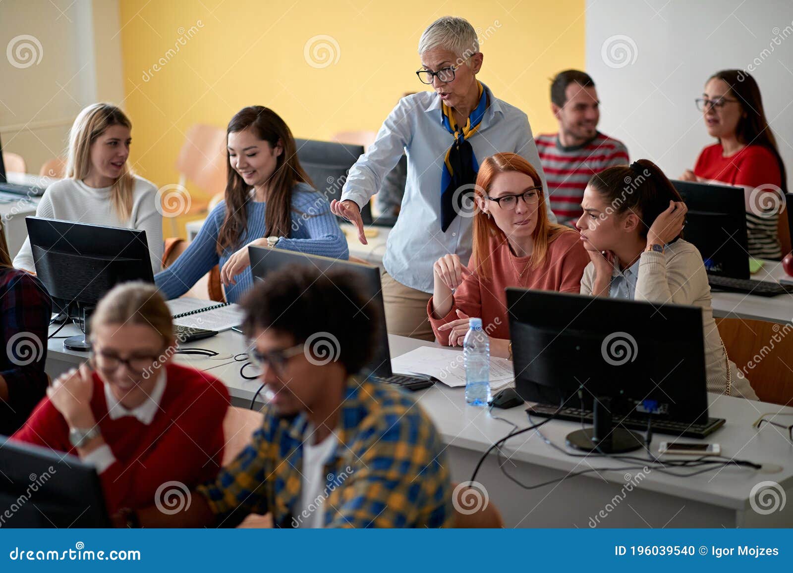 Female Professor Examining the Work of Students at an Informatics ...