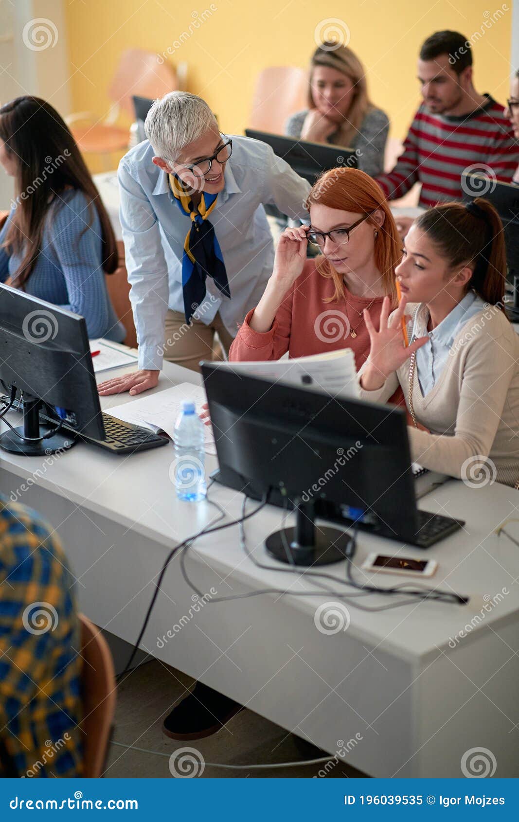Female Professor Giving Help To Students at an Informatics Lecture ...