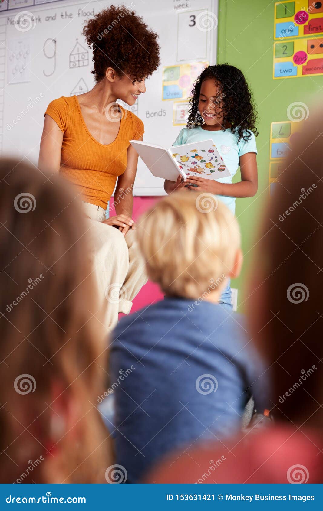 Female Pupil in Elementary School Classroom Reading Book To Class with ...