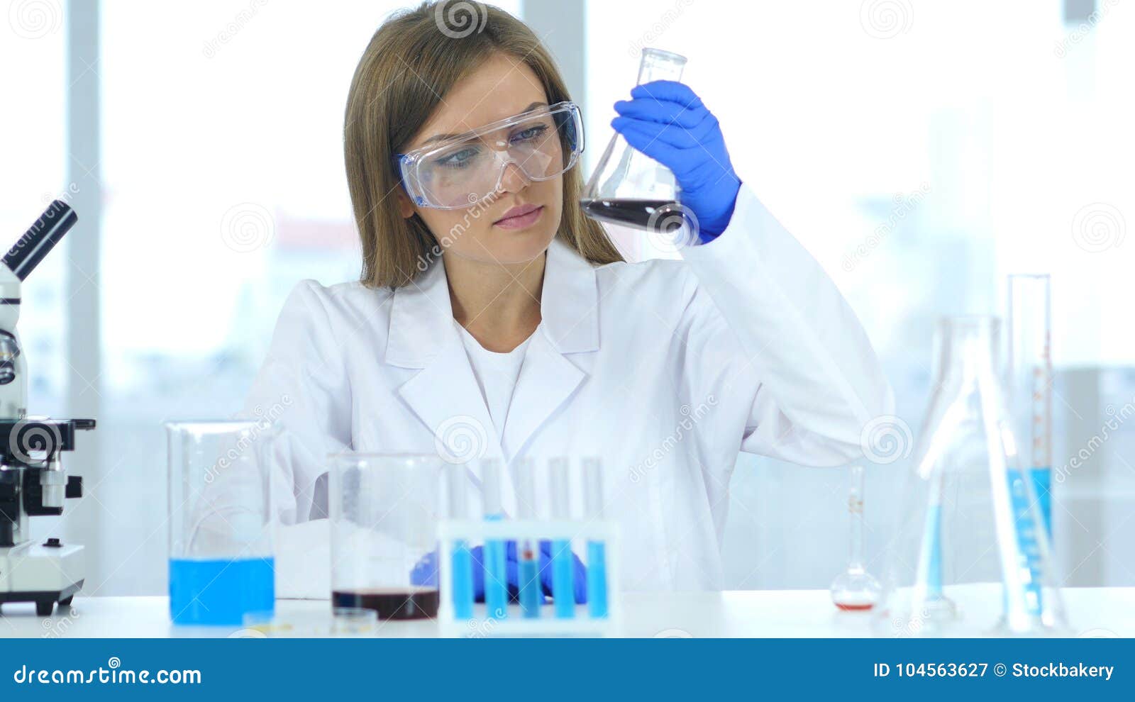 Female Research Scientist Looking at Solution in Beaker in Laboratory ...