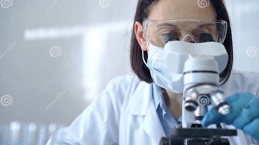 Female Scientist in Lab Goggles, Protective Mask and Gloves is Using ...
