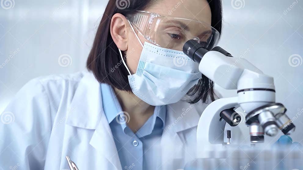 Female Scientist in Lab Goggles, Protective Mask and Gloves is Using ...