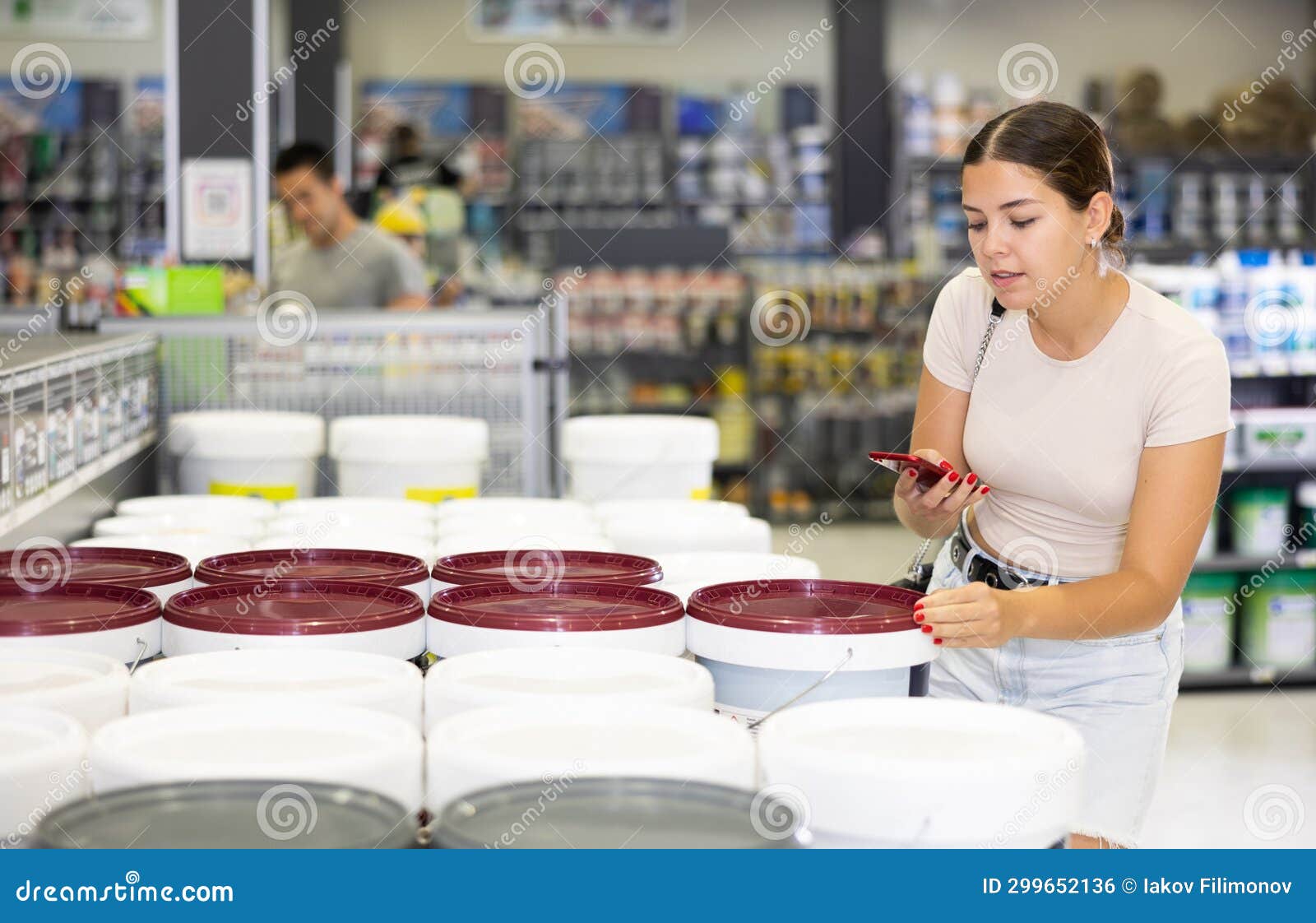 Female Shopper Scanning a QR Code Using a Mobile Phone in Hardware ...