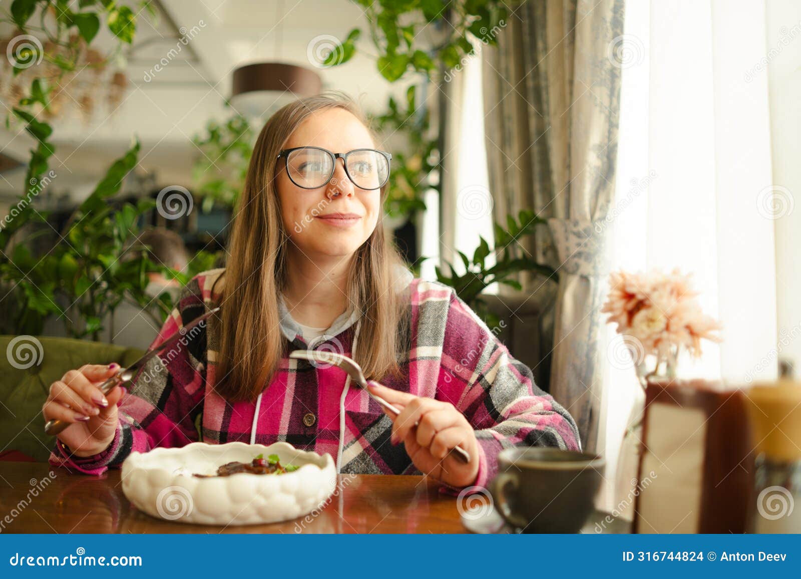 Female Sitting At Table With Plate Of Food A Woman Is Sitting At A