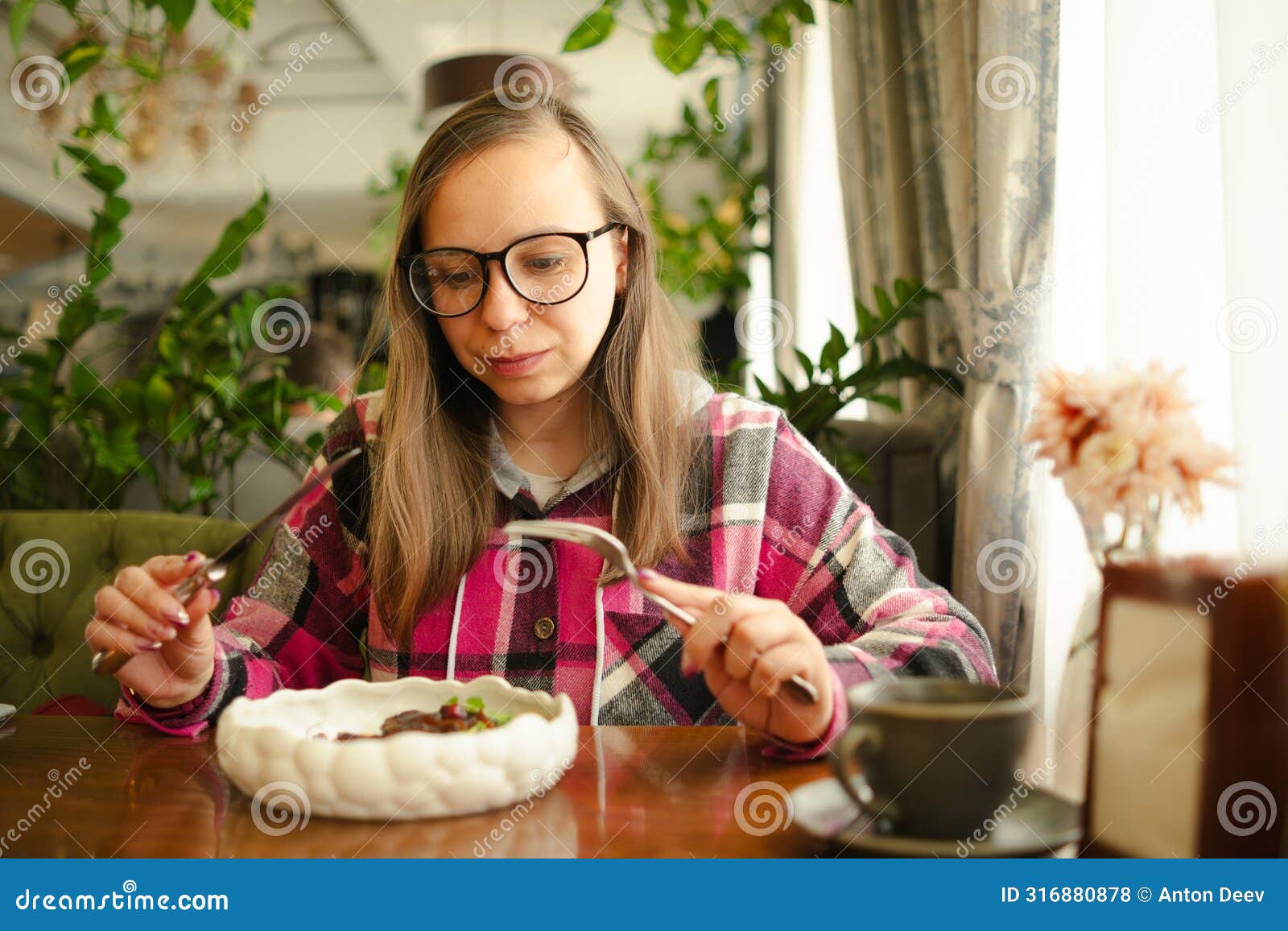 Female Sitting At Table With Plate Of Food A Woman Is Sitting At A