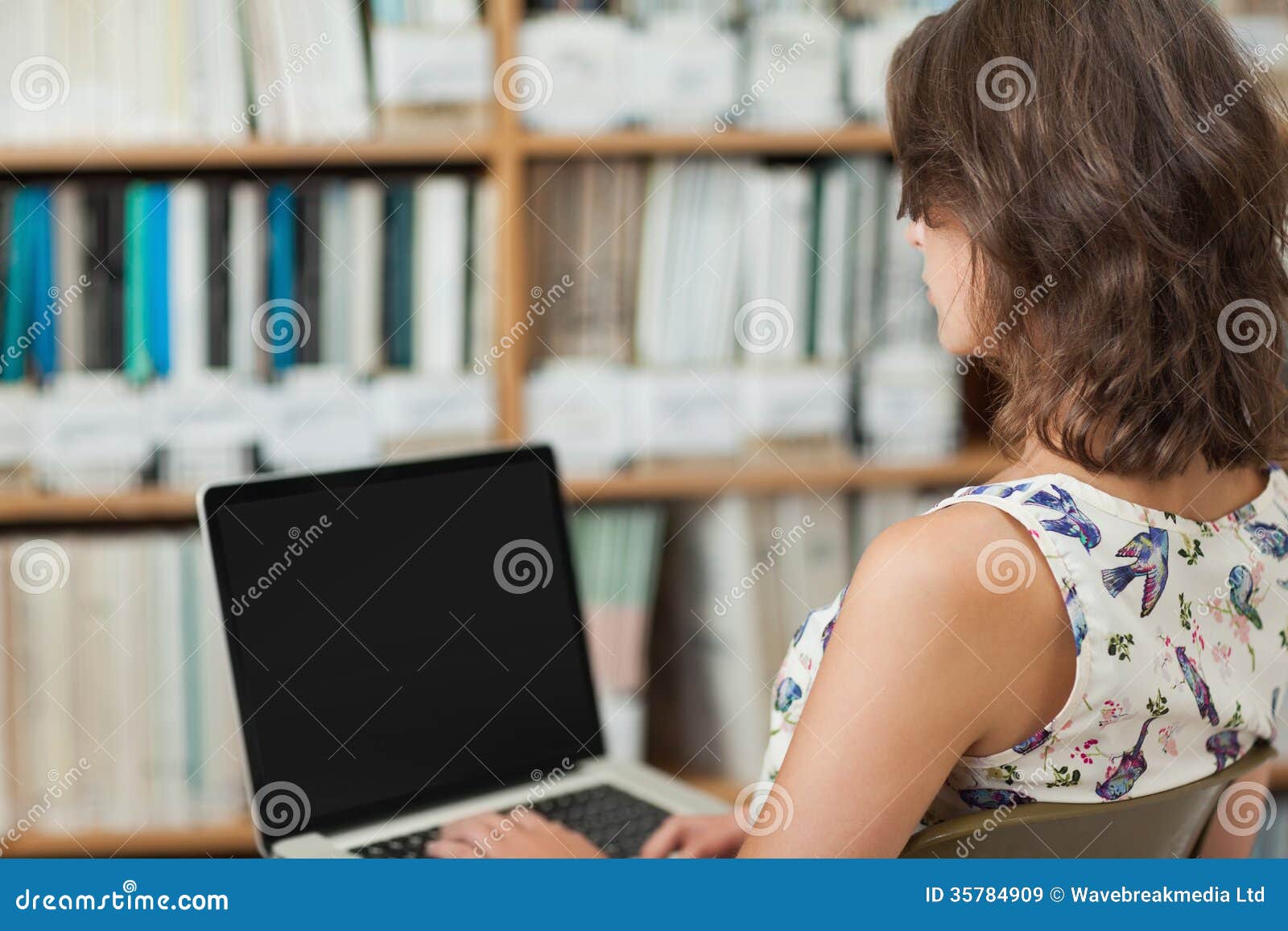 Female Student Against Bookshelf Using Laptop in Library Stock Image ...