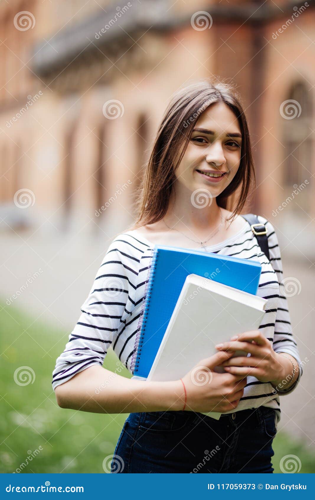 Female Student Outdoors Holding a Notebook and Smiling in Front of Uni ...