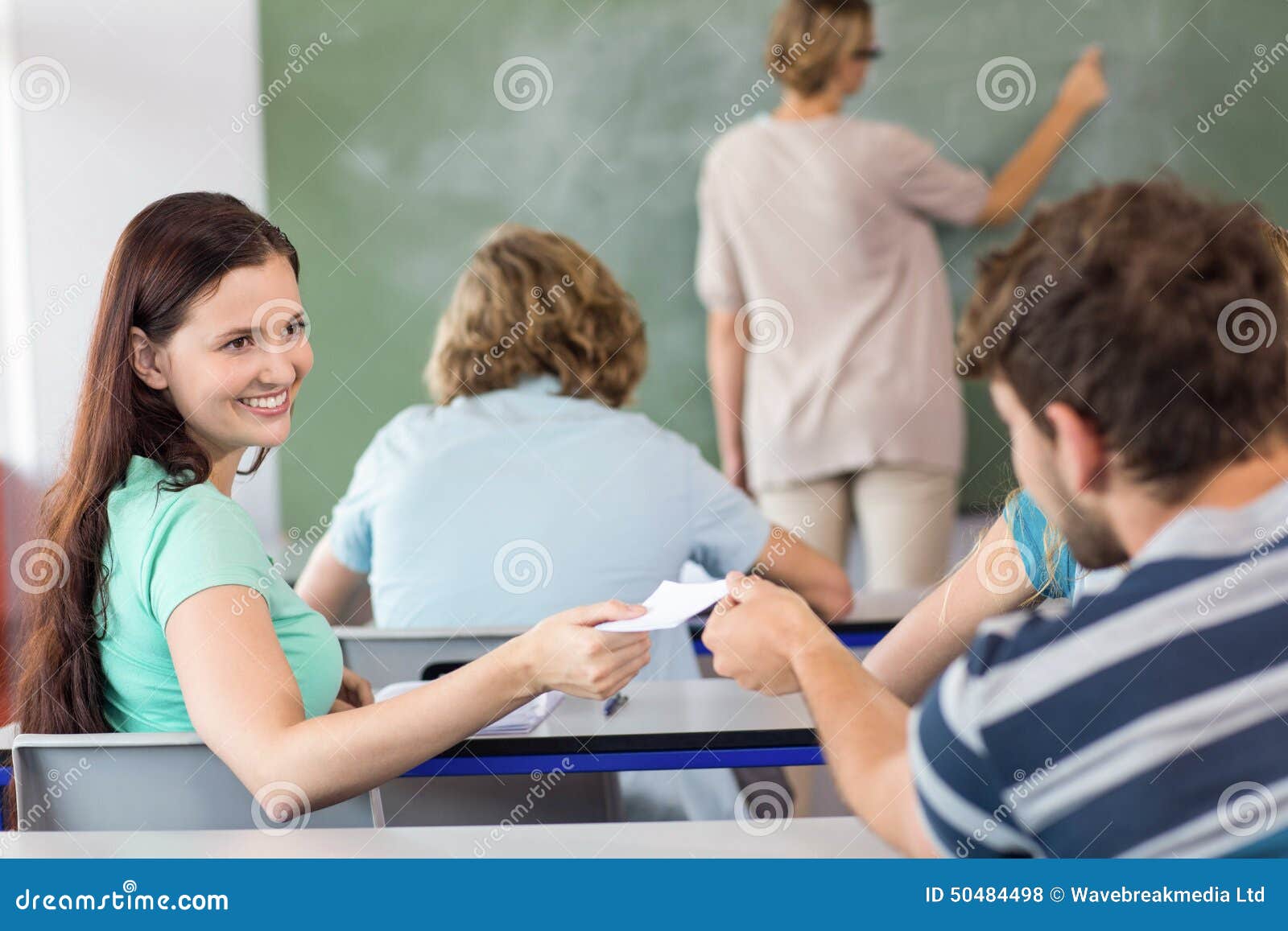Female Student Passing Note To Friend in Classroom Stock Photo - Image ...
