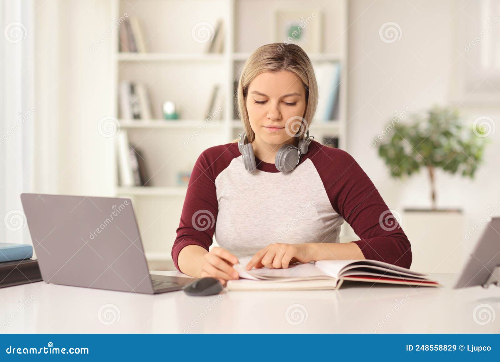 Female Student Studying in Front of a Laptop Computer and Reading a ...