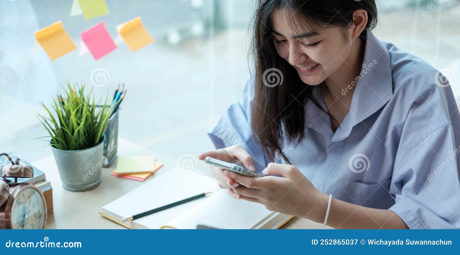 Female Student Taking Notes from a Book and Using Smart Phone at Home ...