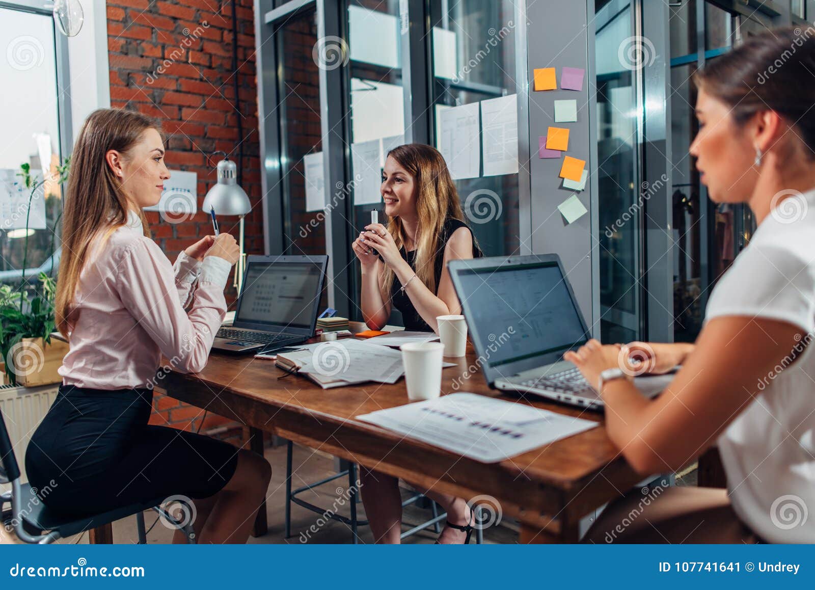 Female Students Working On School Assignment Using Laptops Sitting At ...