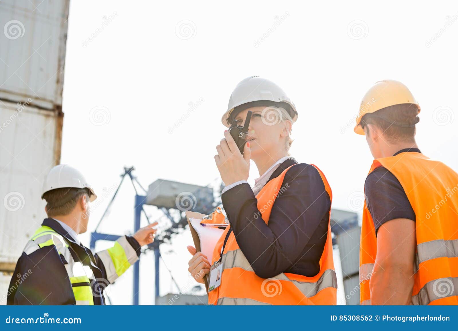 Female Supervisor Using Walkie-talkie while Workers Discussing in ...