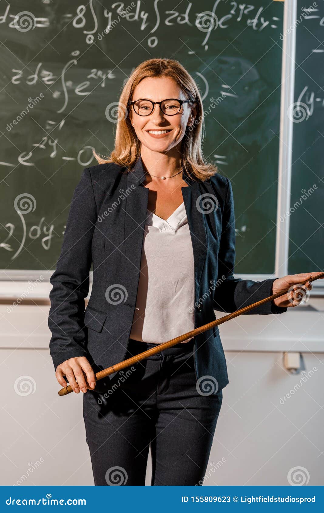 Female Teacher In Formal Wear With Wooden Pointer Explaining
