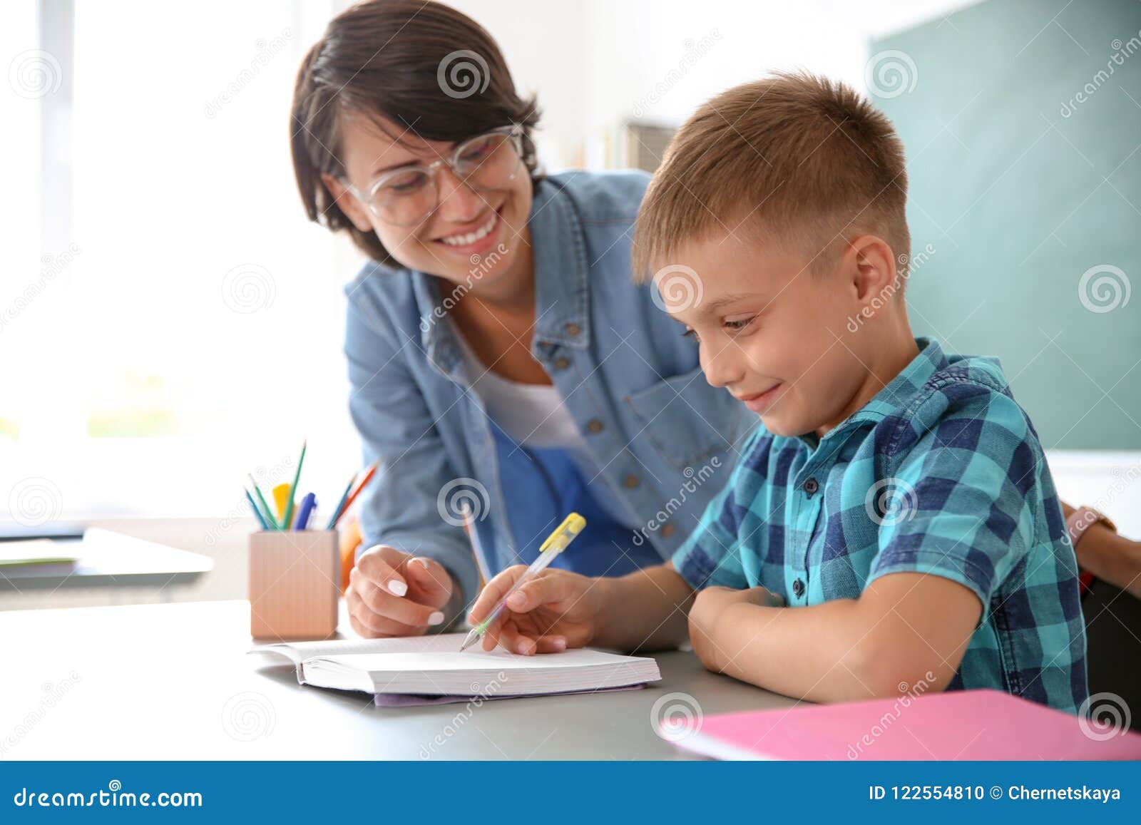 Female Teacher Helping Child with Assignment Stock Photo - Image of ...