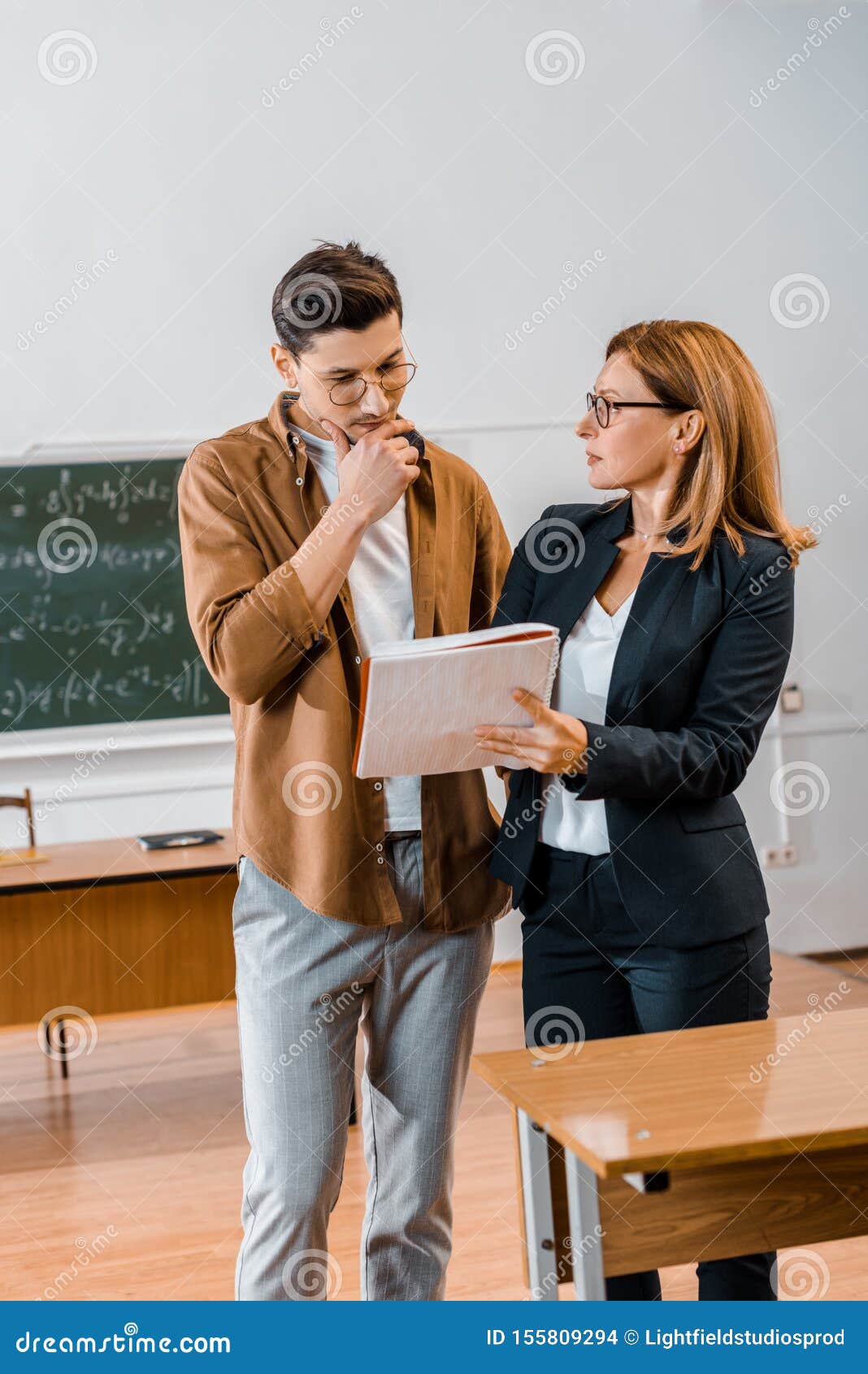 Female Teacher Helping Pensive Male Student with Assignment during ...