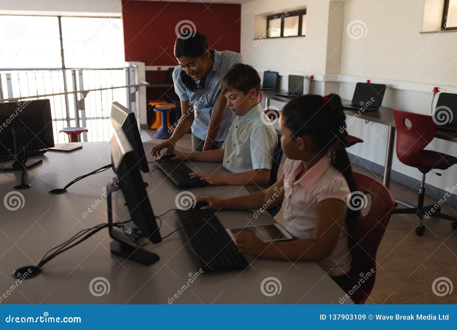 Female Teacher Teaching Computer To Schoolkid at Desk in School Stock ...