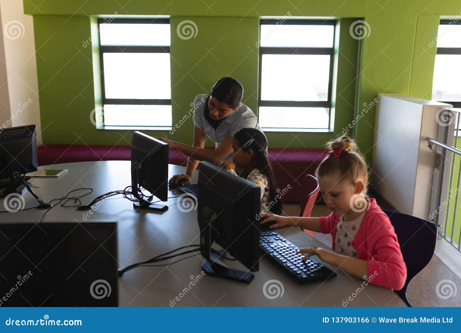 Female Teacher Teaching Computer To Schoolkid at Desk in School Stock ...