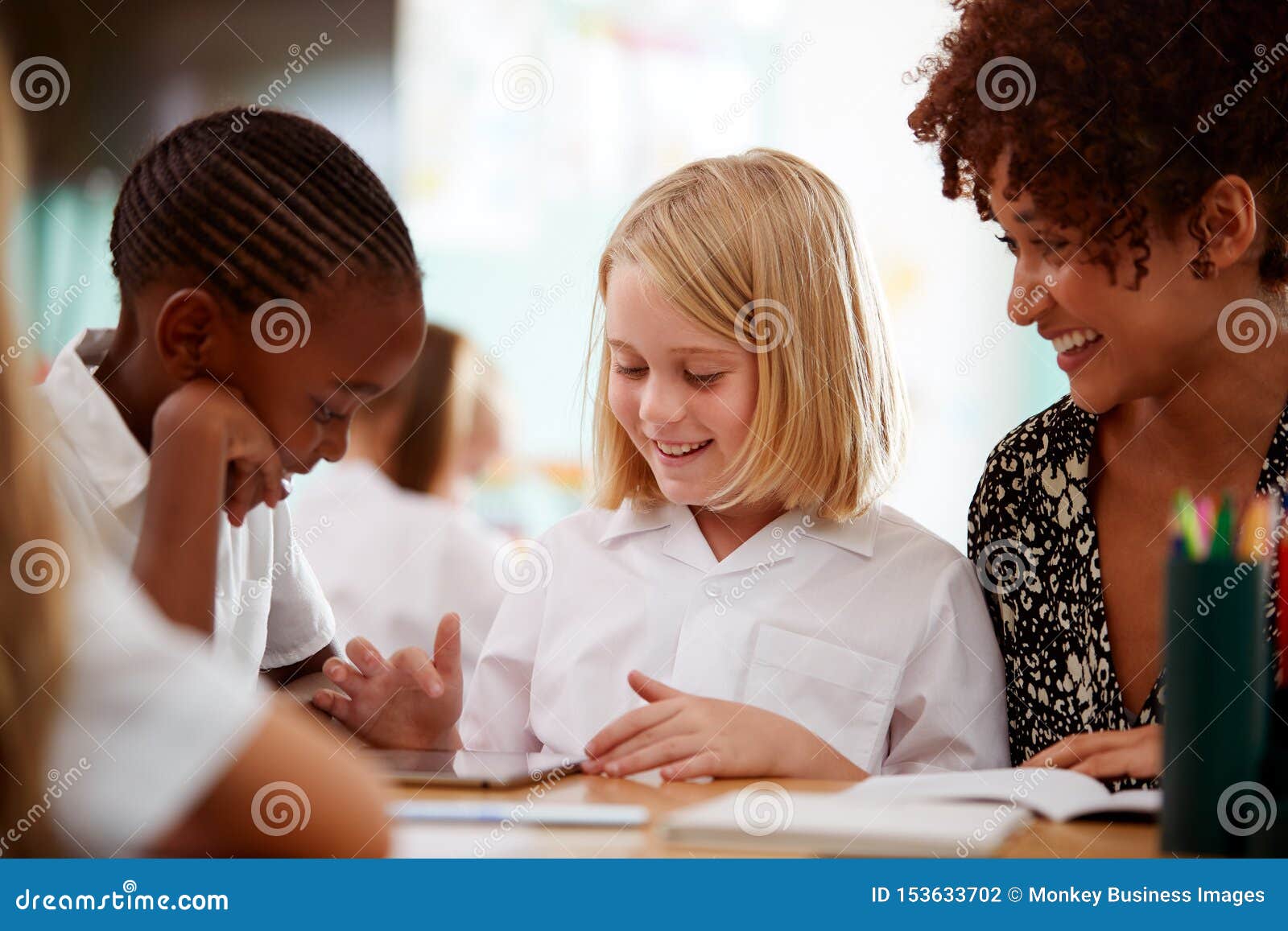 Female Teacher with Two Elementary School Pupils Wearing Uniform Using ...