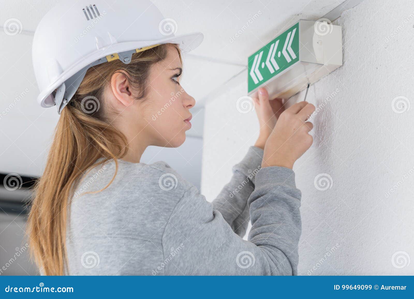 Female Technician Placing Emergency Exit Sign Stock Image - Image of ...