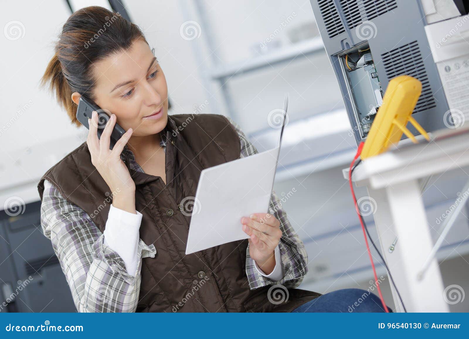 Female Technician Reading Manual and Speaking on Phone Stock Photo ...