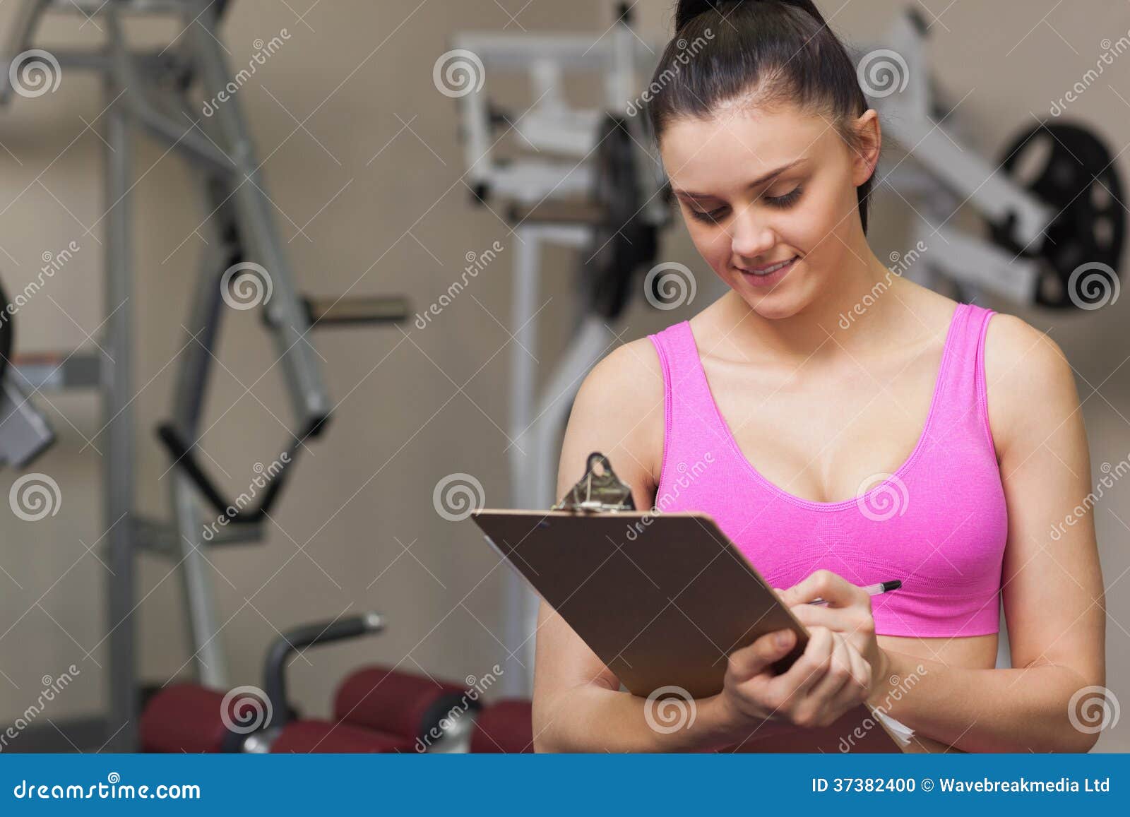 Female Trainer Writing on Clipboard in Gym Stock Photo - Image of ...