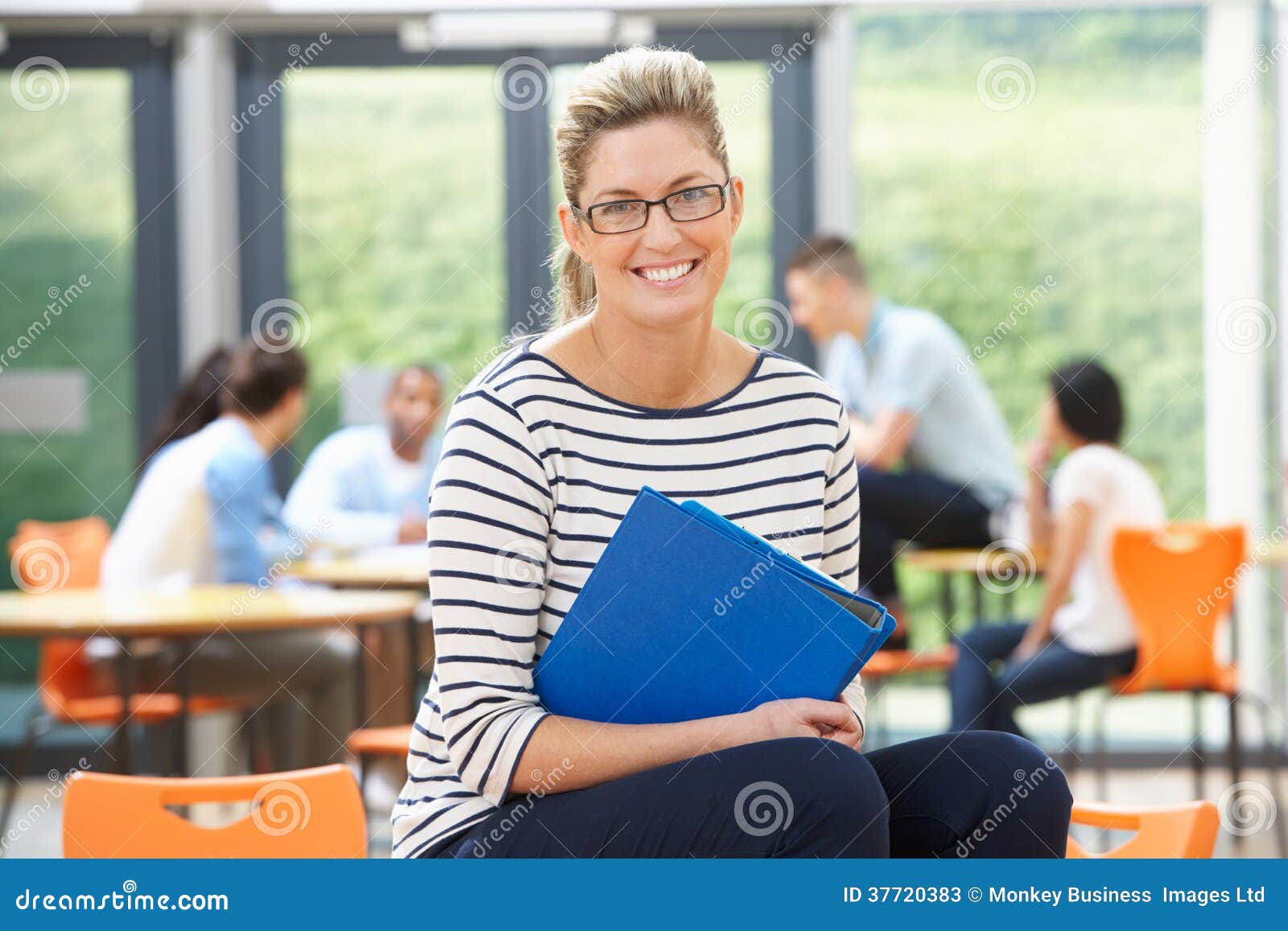 Female Tutor Sitting in Classroom with Folder Stock Image - Image of ...