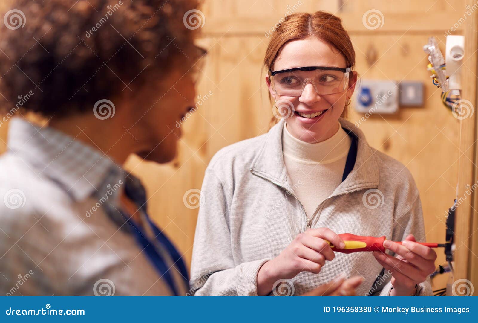 Female Tutor with Trainee Electrician in Workshop Studying for ...