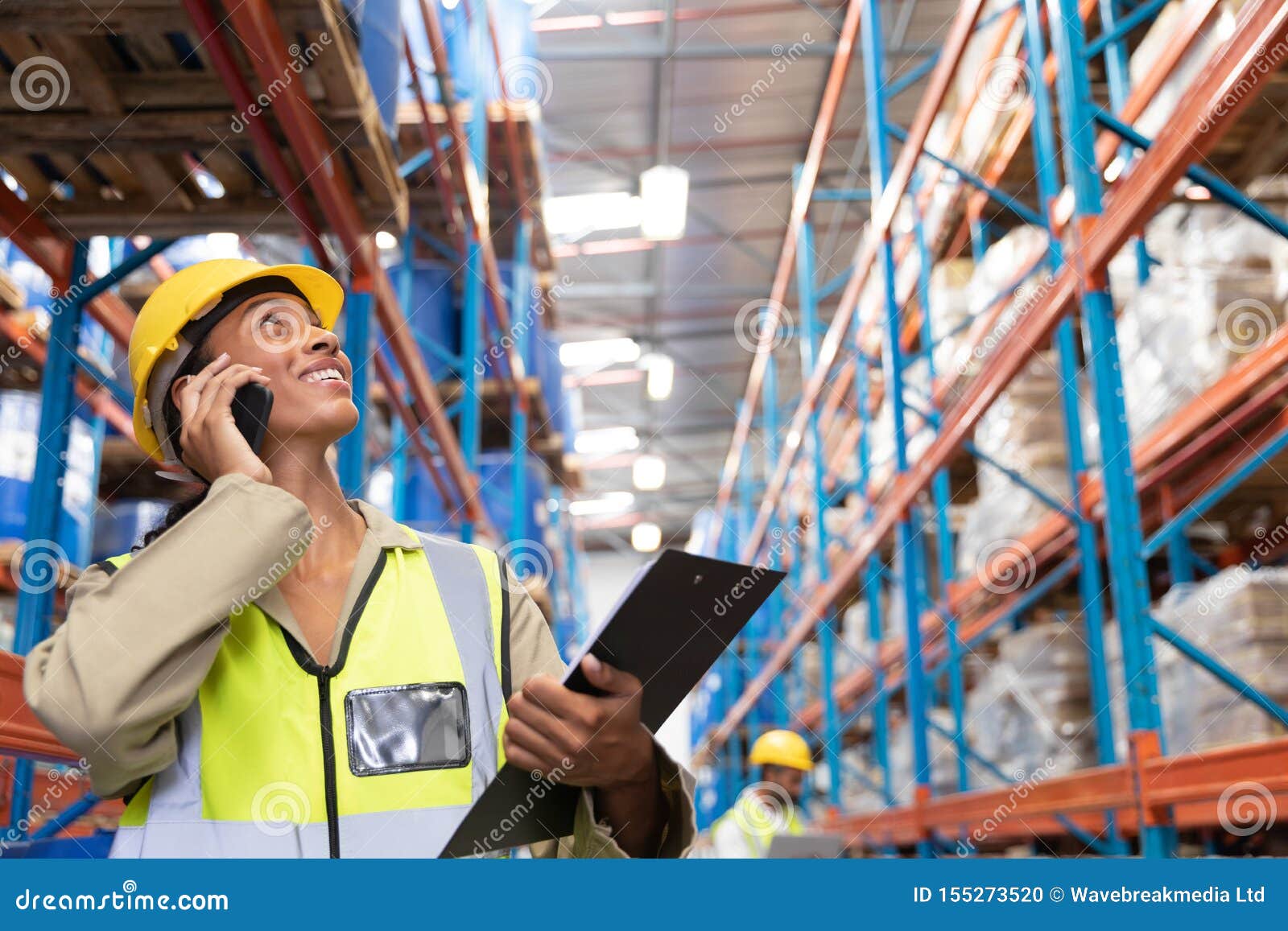 Female Worker Looking Up while Talking on Mobile Phone in Warehouse ...