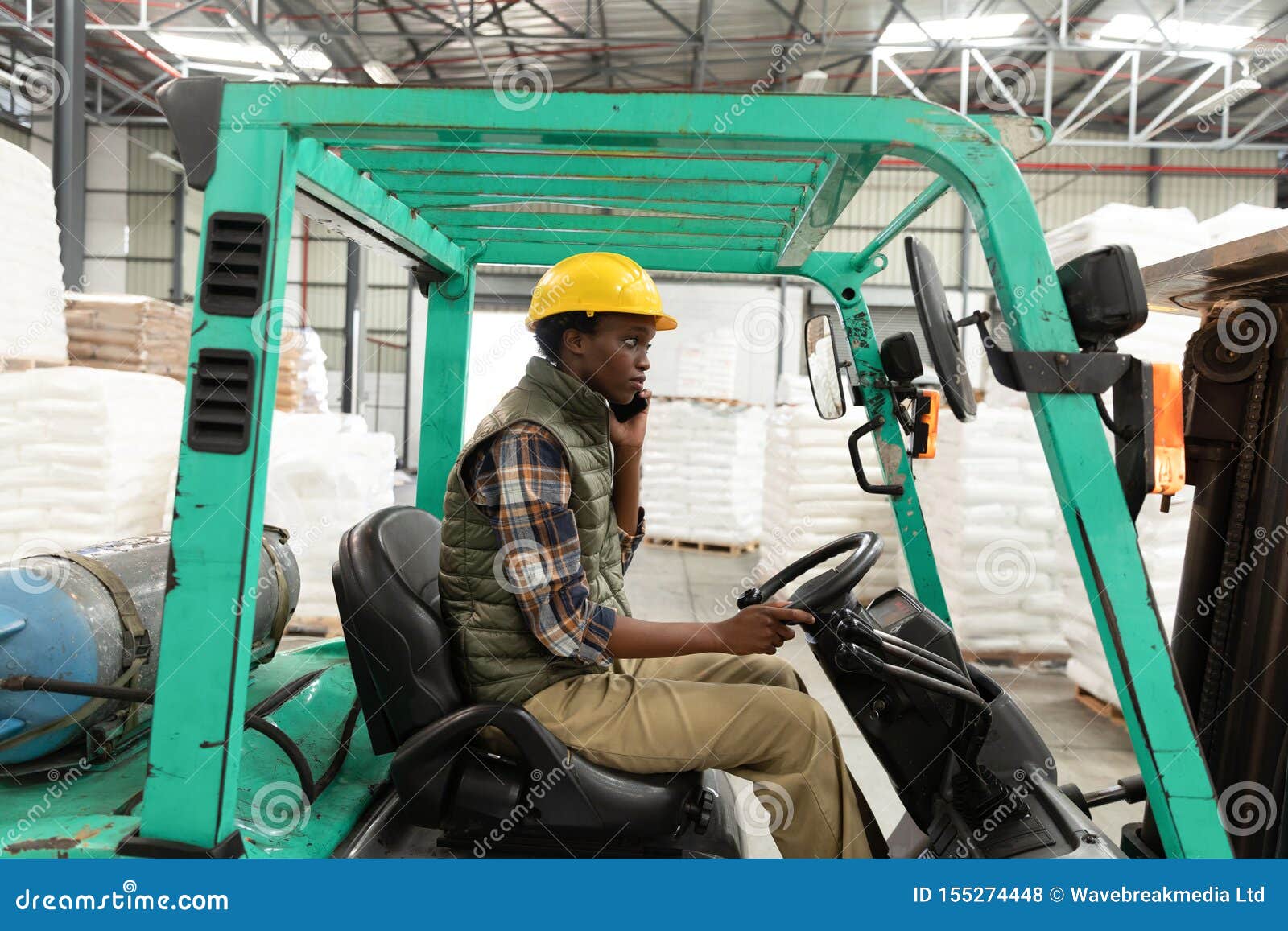Female Worker Talking on Mobile Phone while Driving Forklift in ...