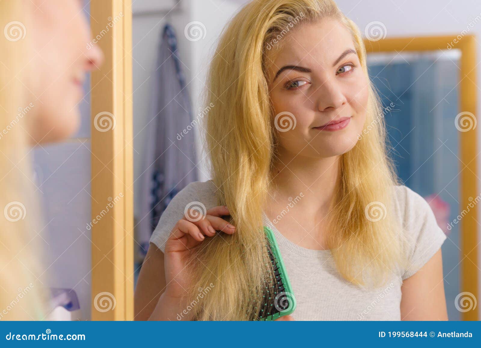 Femme Se Brossant Les Cheveux Blonds Dans La Salle De Bain Photo Stock