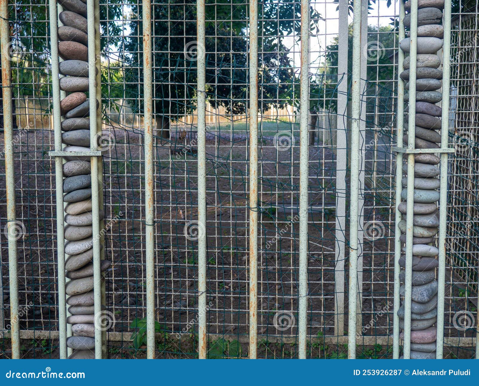 A Fence Made of Rods and Stacked Stones. Stacked Pebbles Stock Image ...